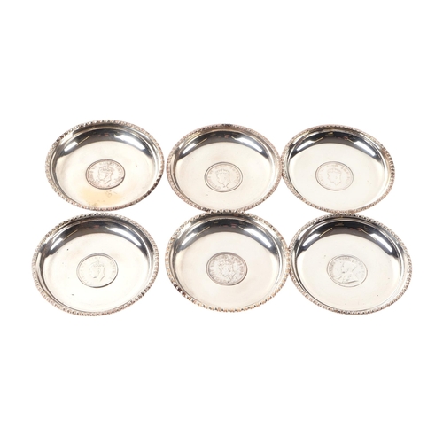 A set of six white metal coin set dishes, each set with a 1 1/4 Ana ...