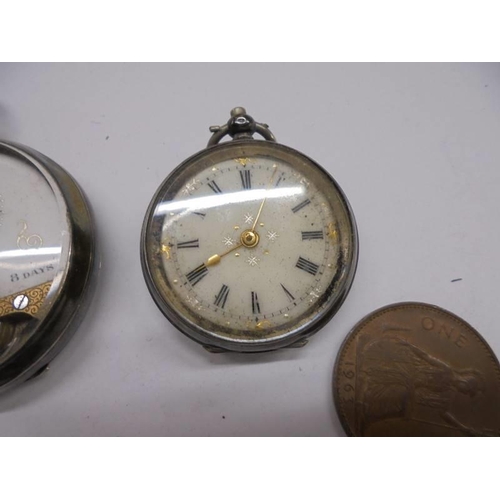 A lady's silver fob watch, a pocket watch and four coins.