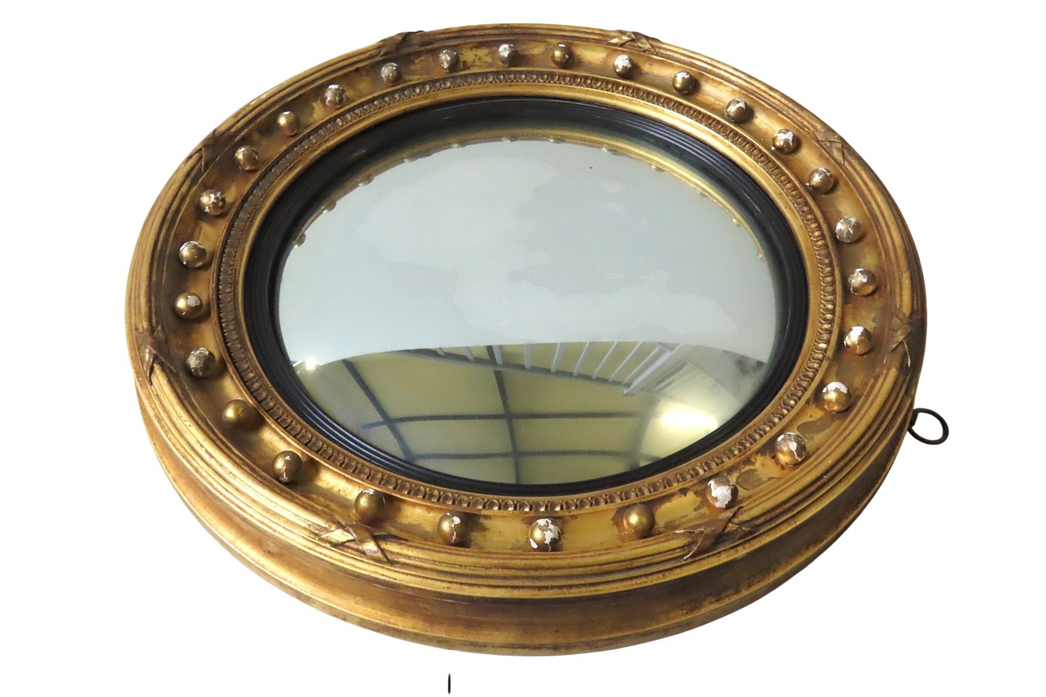A CIRCULAR CONVEX MIRRORin a gilt gesso frame with ball finial ...