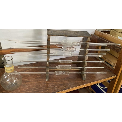 Scientific glass pipettes, mainly Pyrex seated on a wooden rack ...