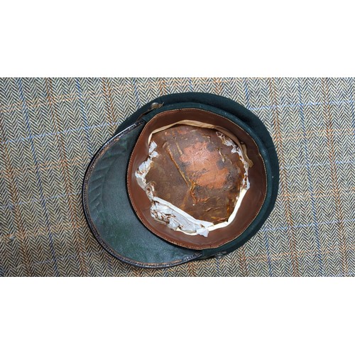 A military-style peaked cap with green crown, black band and patent ...