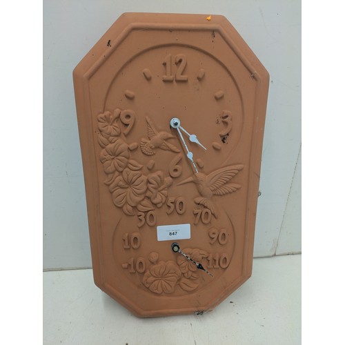 A terracotta wall clock and thermostat