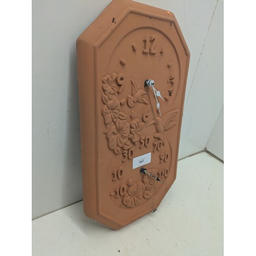 A terracotta wall clock and thermostat