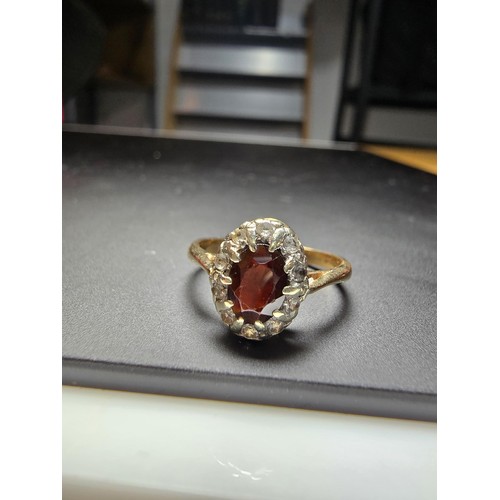 A hallmarked 9ct yellow gold ring inset with a large garnet stone ...