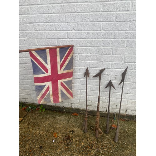 A group of antique whale harpoons, and a union flag on pole