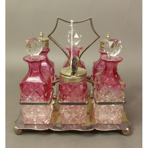 Graduated clear to cranberry glass six-piece cruet set on a rectangular ...