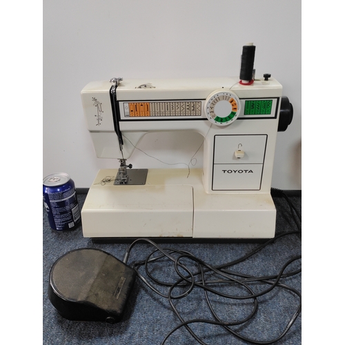 A vintage Toyota sewing machine with peddle, accessories and cover.