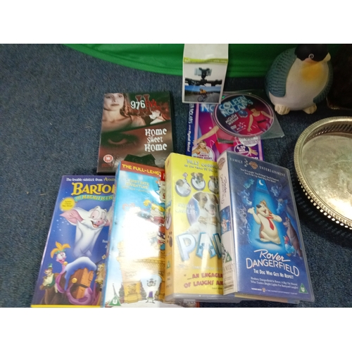 A collection of items. To include a penguin piggy bank, 2 CD's, 4 VHS's, 2 Dvd's, a bike phone holde