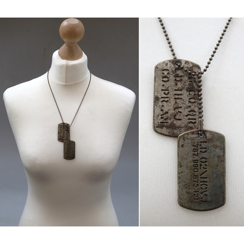 A pair of military-style metal identity tags, each suspended on a ball ...