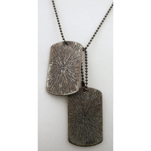 A pair of military-style metal identity tags, each suspended on a ball ...