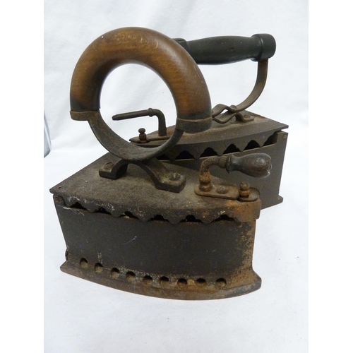 Two cast iron clothes irons, the handles and covers lift to reveal a ...