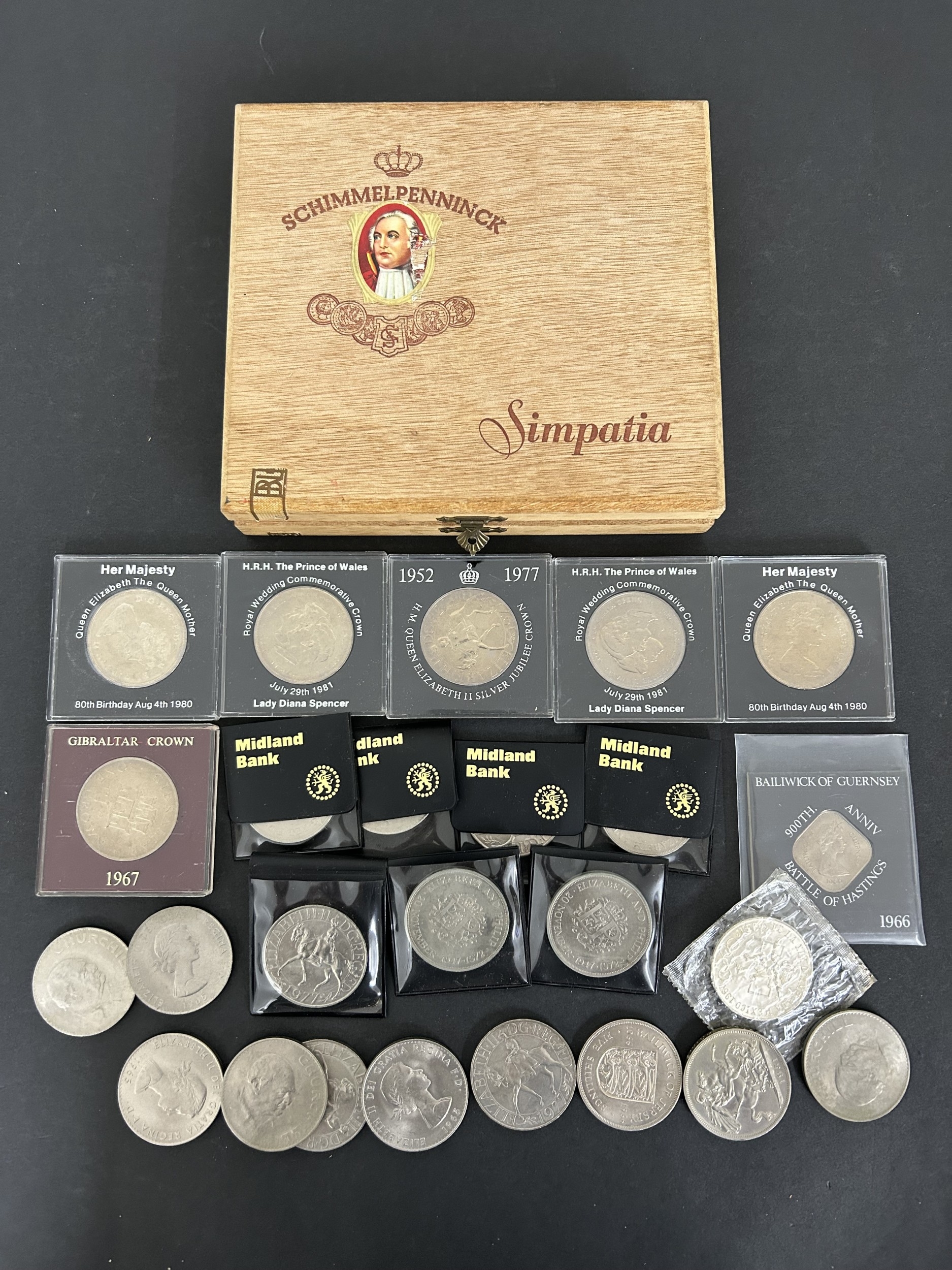 A wooden cigar box containing mixed commemorative coins