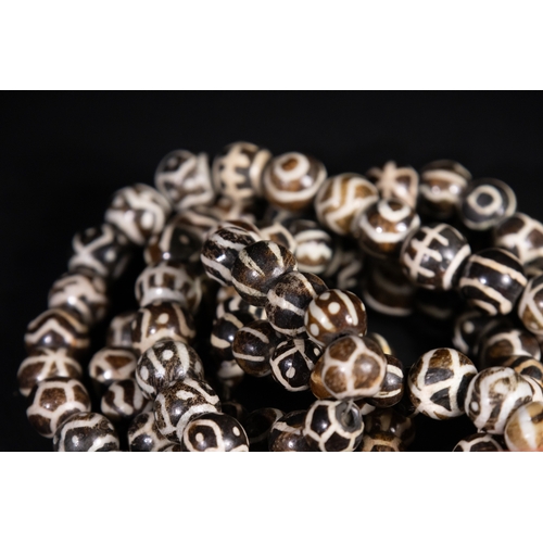 A Tibetan Strand of Etched Dzi Beads with Red Tassel. A coiled Tibetan ...