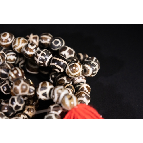 A Tibetan Strand of Etched Dzi Beads with Red Tassel. A coiled Tibetan ...