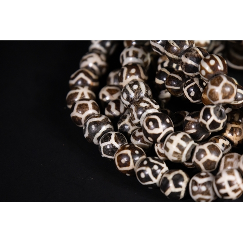 A Tibetan Strand of Etched Dzi Beads with Red Tassel. A coiled Tibetan ...