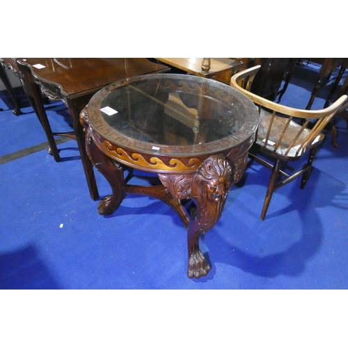 A heavily carved hardwood circular topped occasional table with a glass ...