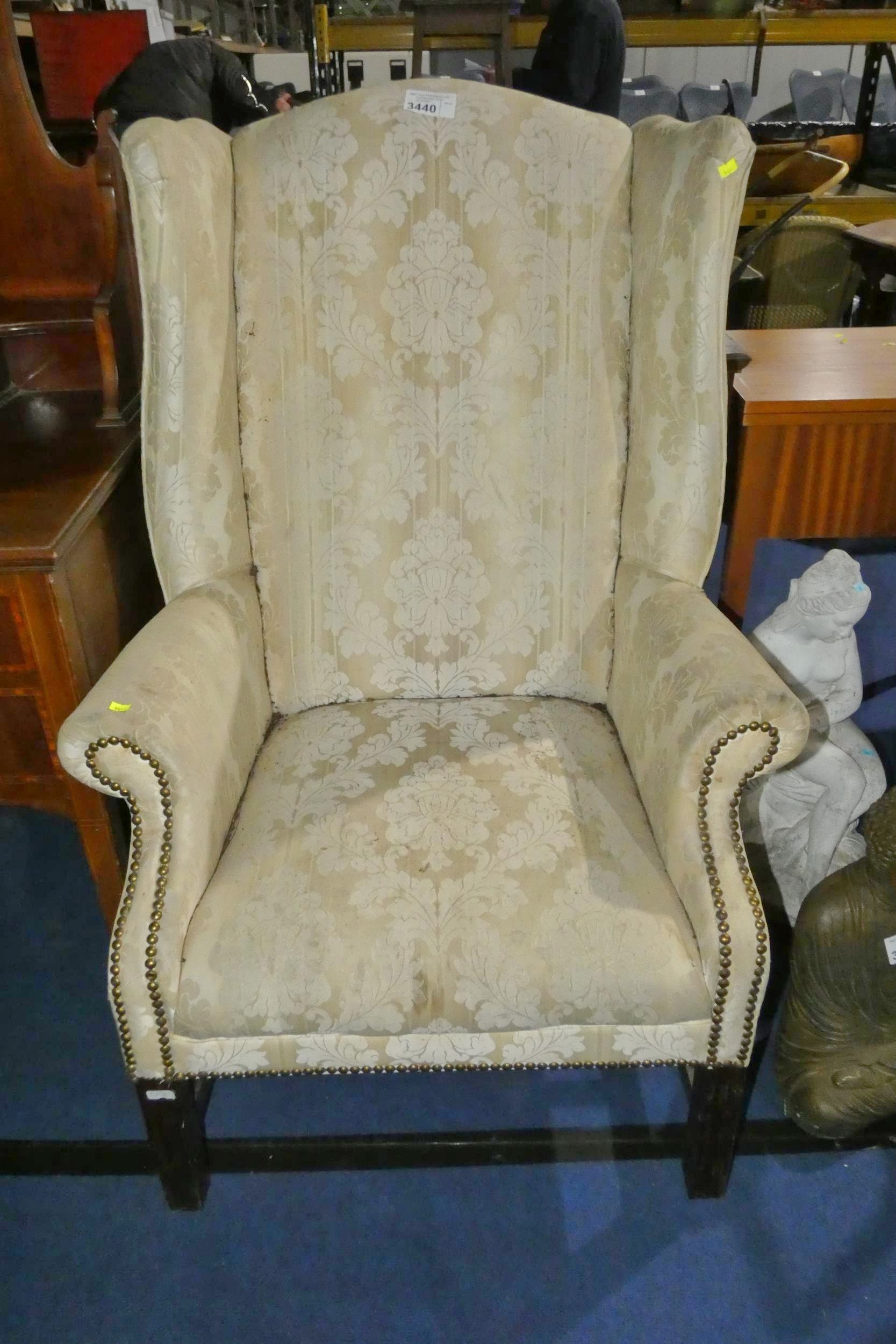 A high back wing armchair with cream brocade upholstery