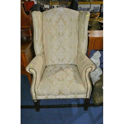 A high back wing armchair with cream brocade upholstery
