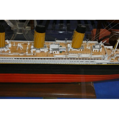 A perspex display cabinet containing a wooden model of RMS Titanic