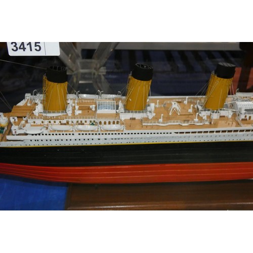 A perspex display cabinet containing a wooden model of RMS Titanic