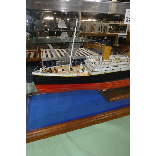 A perspex display cabinet containing a wooden model of RMS Titanic