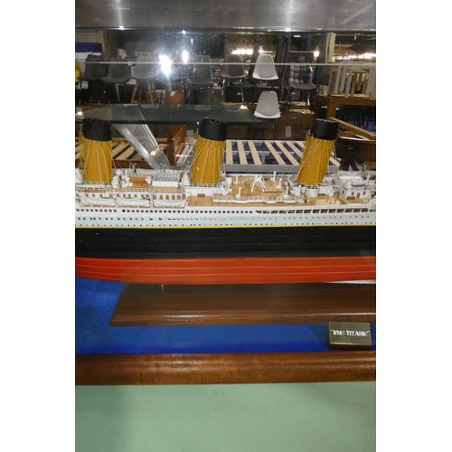 A perspex display cabinet containing a wooden model of RMS Titanic