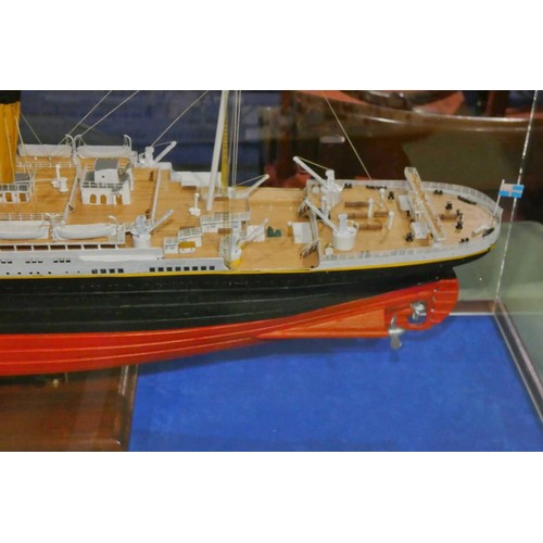 A perspex display cabinet containing a wooden model of RMS Titanic