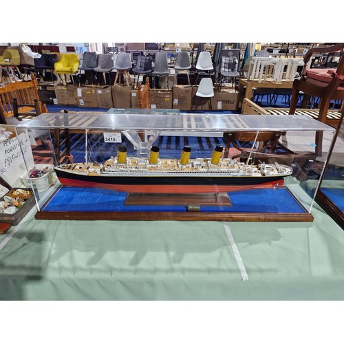 A perspex display cabinet containing a wooden model of RMS Titanic