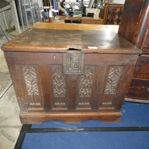 A heavily carved dark oak storage chest with a panelled front and lift lid