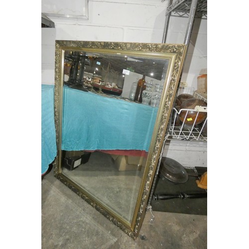 A large rectangular beveled wall mirror in a decorative gilt frame