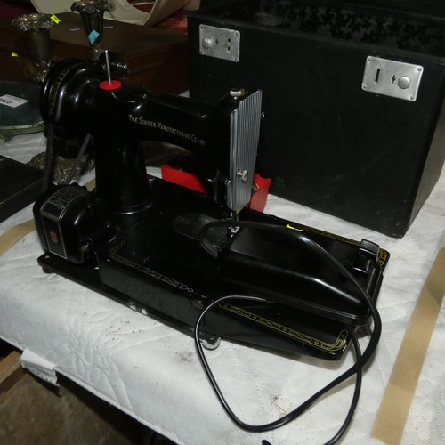 A small vintage Singer electric sewing machine with carry case