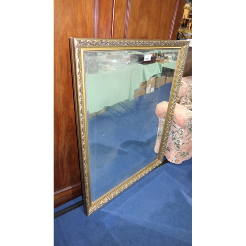 A large rectangular beveled wall mirror in an ornate gilt frame