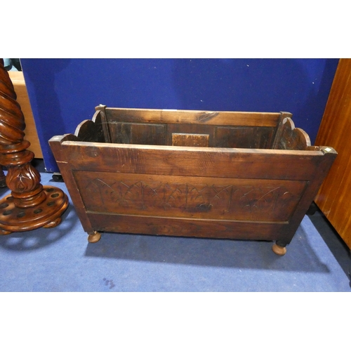 A large carved oak log box with panelled sides and an open top