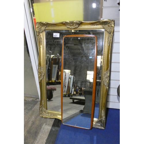 A large rectangular beveled wall mirror in an ornate gilt frame and a ...
