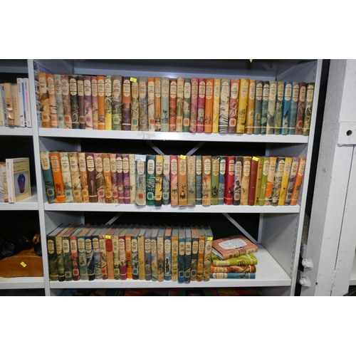 A collection of hardbacked books mainly novels (three shelves)