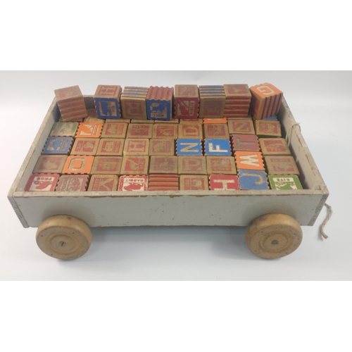 A child's vintage wooden pull-along trolley filled with wooden blocks ...