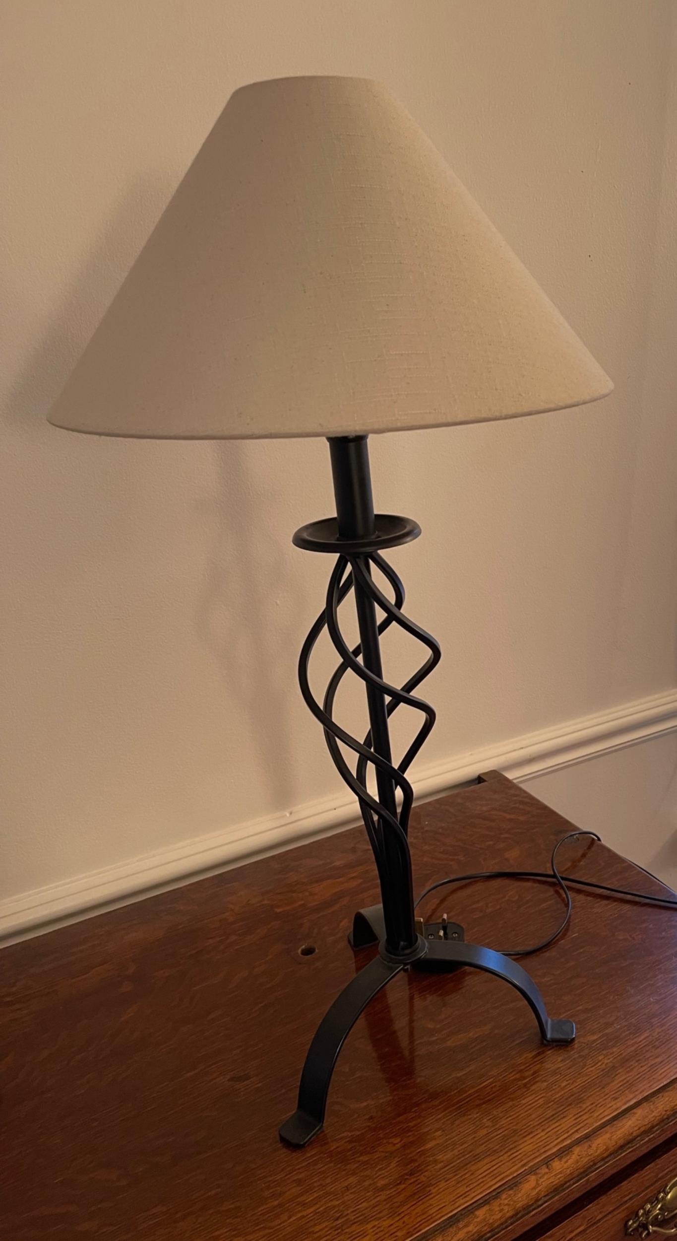 A modern electric table lamp with white shade with a fancy wire-work ...