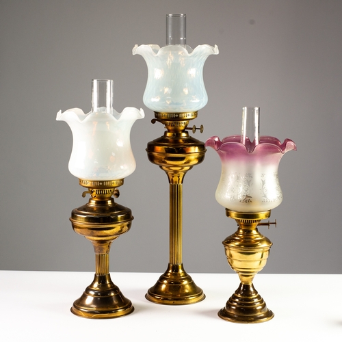 PARAFFIN LAMPS: Three similar brass paraffin lamps of varying size ...