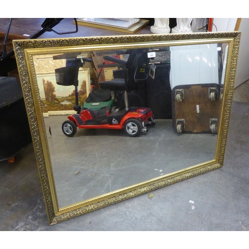 A LARGE RECTANGULAR BEVELLED EDGE WALL MIRROR, IN EMBOSSED GILT FRAME ...