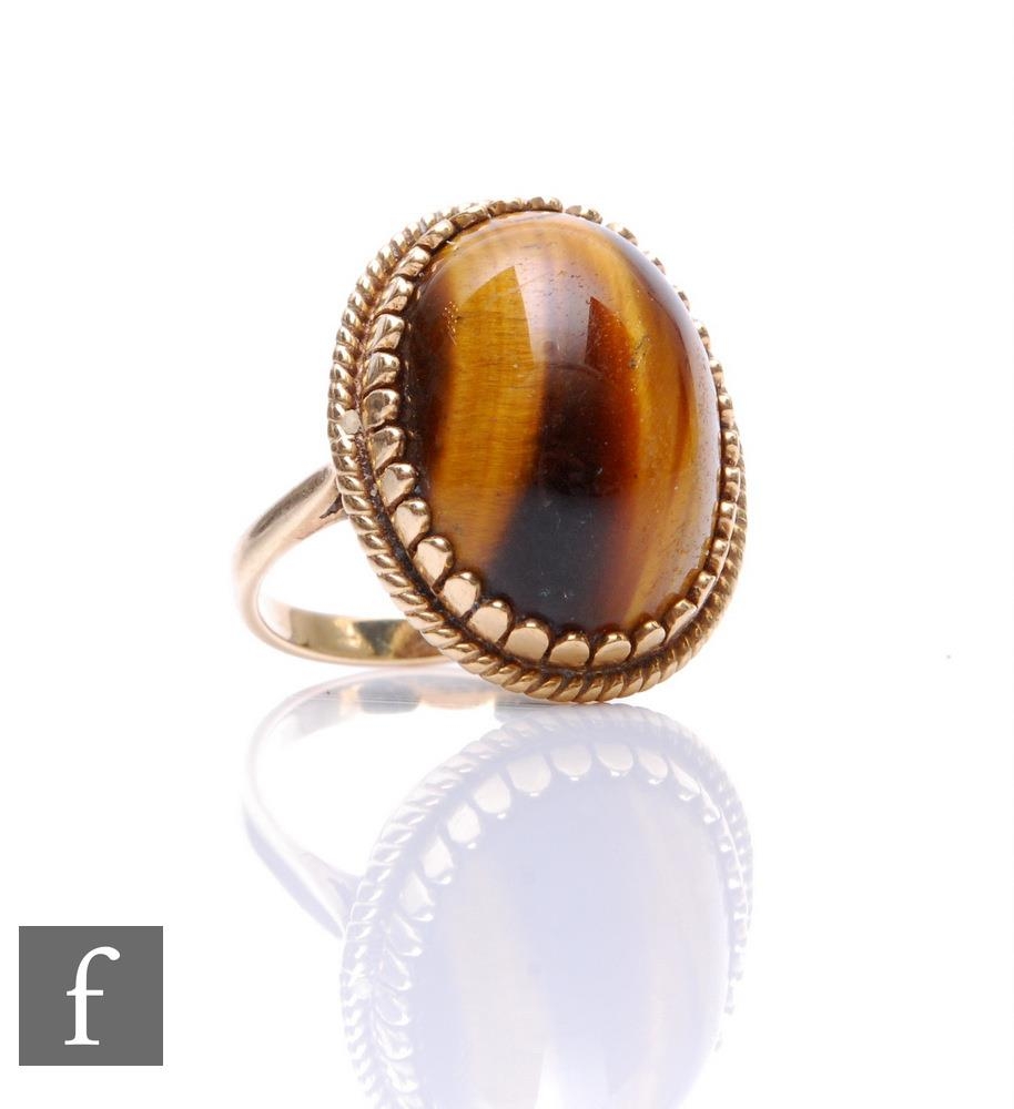 An 9ct hallmarked single stone oval tigers eye ring, cabochon cut stone ...