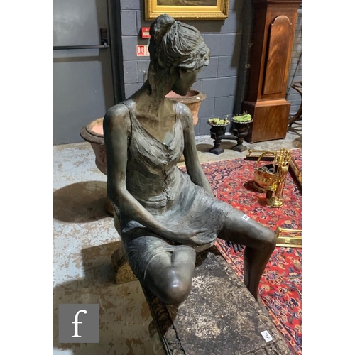 A life size cast metal figure of a female, cast in seated position and ...
