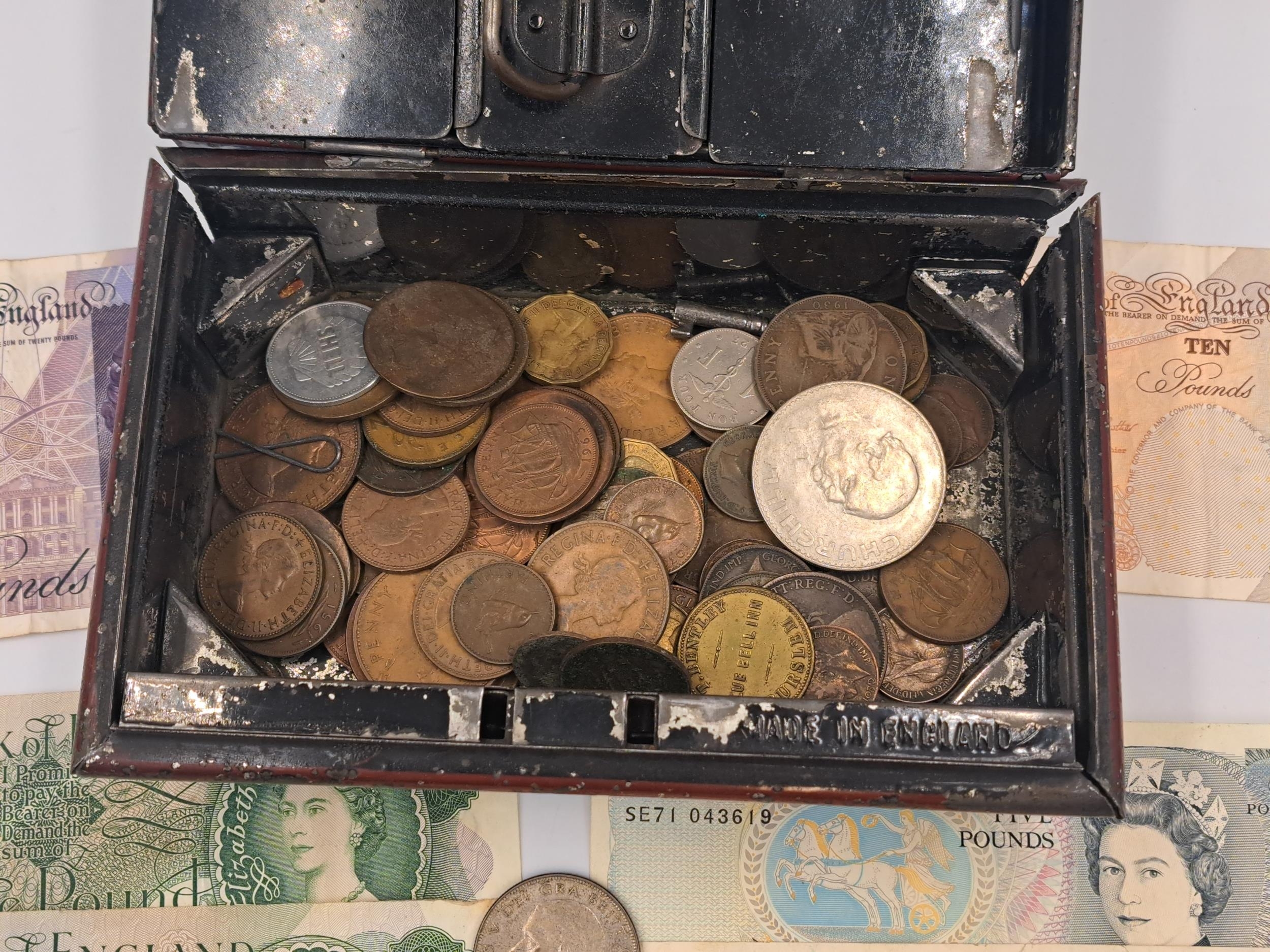 A vintage change tin containing a collection of British banknotes and ...