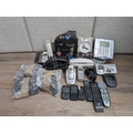 A collection of landline telephones, remote controls and mobile phones ...