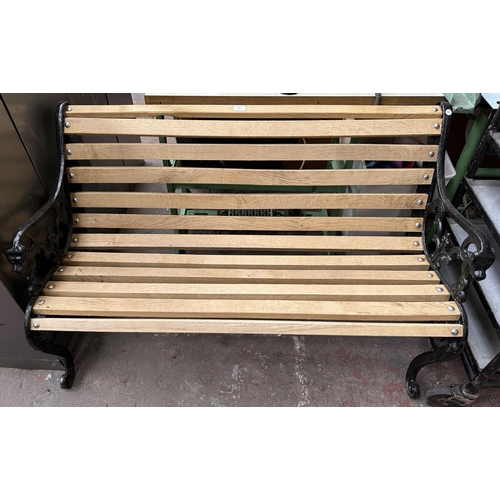 A Victorian style black painted cast iron and oak slatted garden bench ...