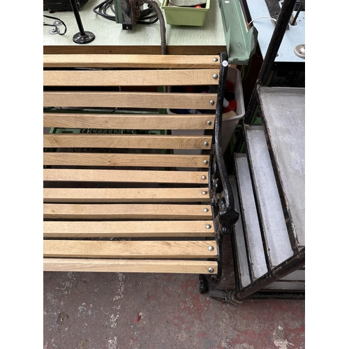A Victorian style black painted cast iron and oak slatted garden bench ...