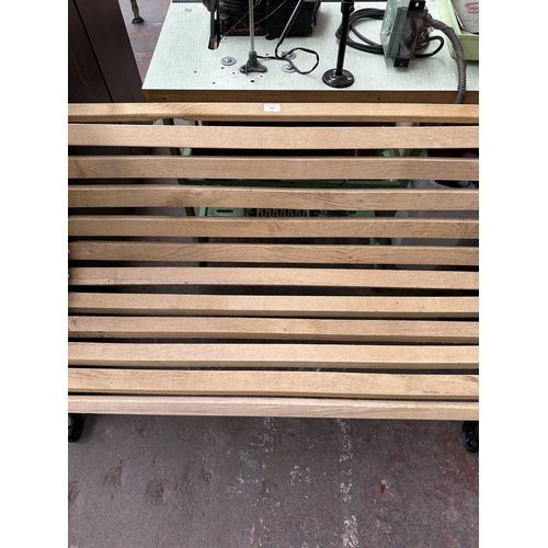 A Victorian style black painted cast iron and oak slatted garden bench ...