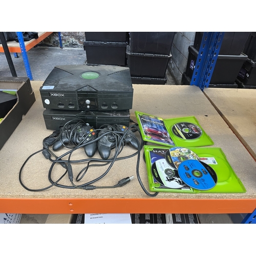 Two Xbox consoles with two controllers and four game discs