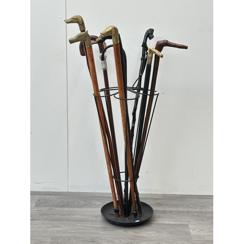 A black painted wrought metal five section stick stand containing eight ...