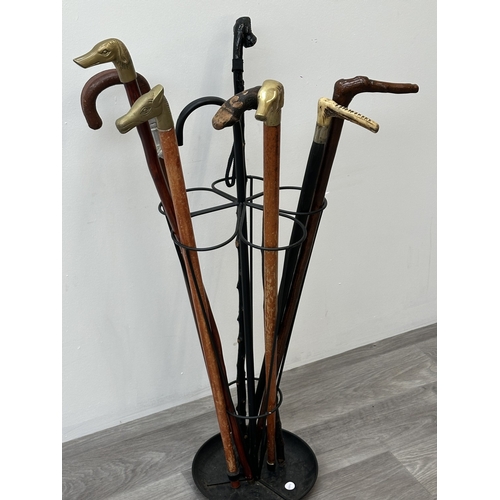 A black painted wrought metal five section stick stand containing eight ...
