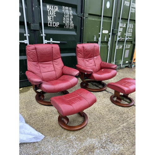 A pair of EKORNES red leather reclining chairs with matching footstools
